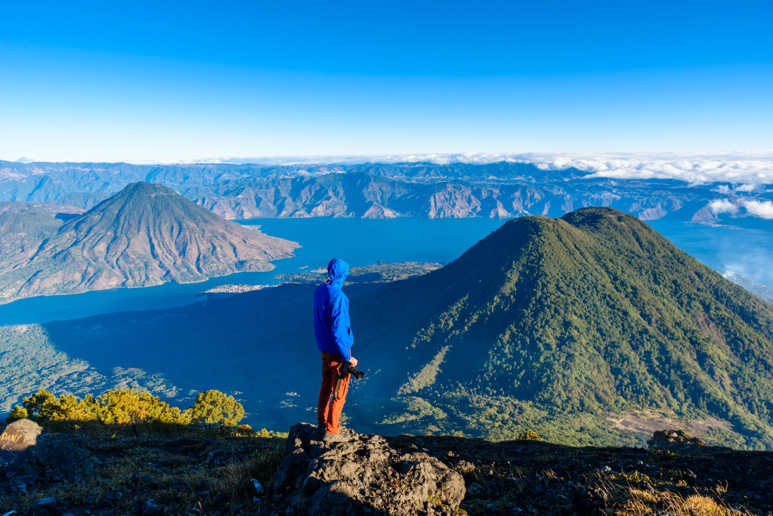 Hiker with panorama view of Lake Atitlan and volcano San Pedro and ...